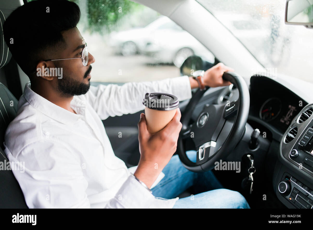 transportation and vehicle concept - man drinking coffee while driving ...