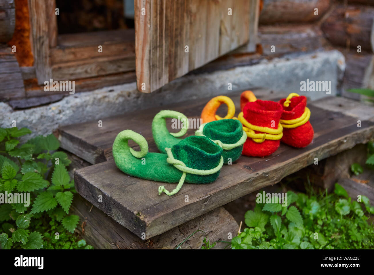 Two pairs of dwarf felt shoes at the entrance of an old wooden house ...