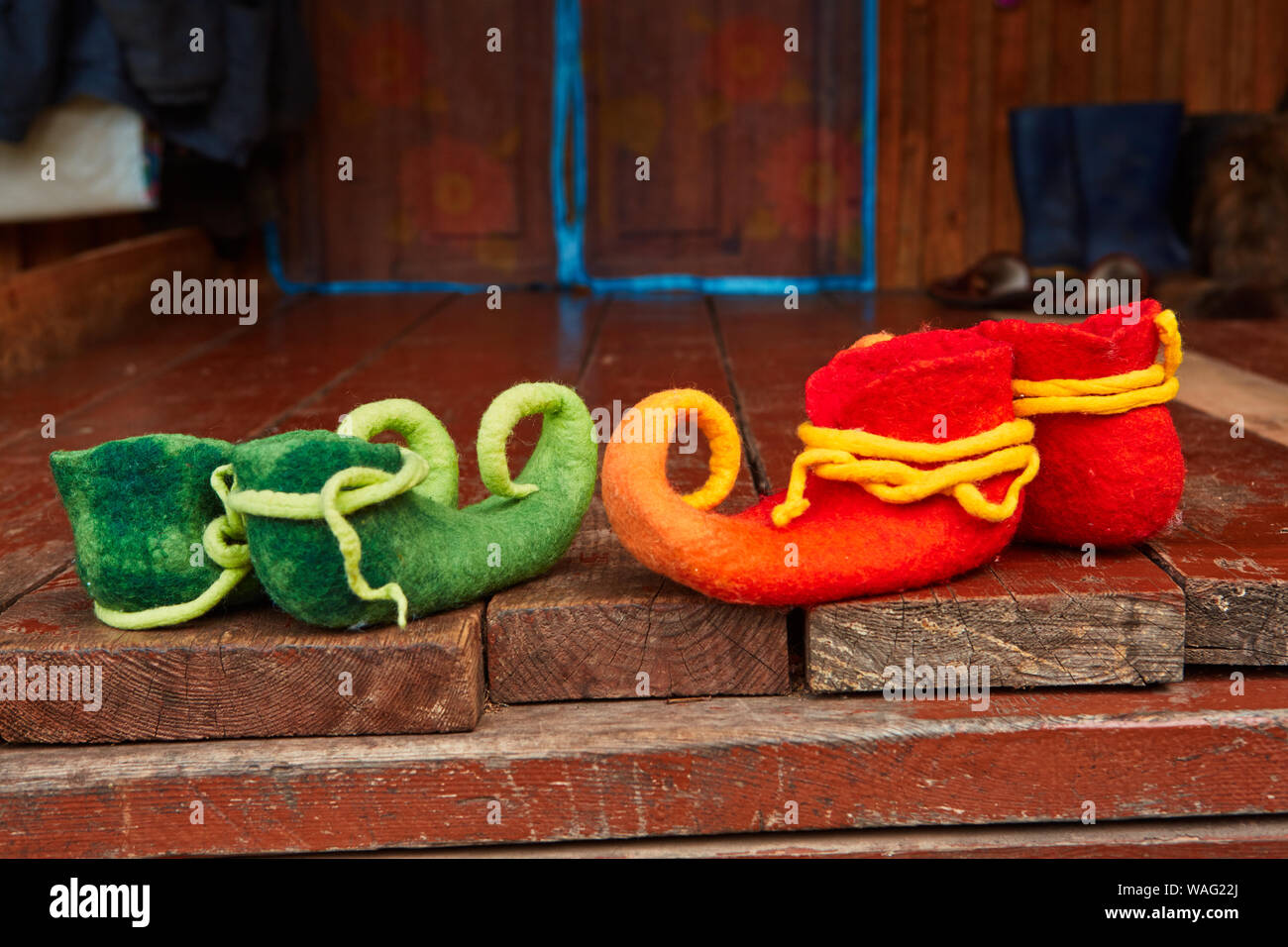 Two pairs of dwarf felt shoes at the entrance of an old wooden house ...