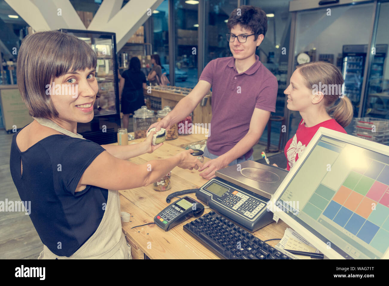 Female shop assistant serving a couple at a desk. Paying for products ...