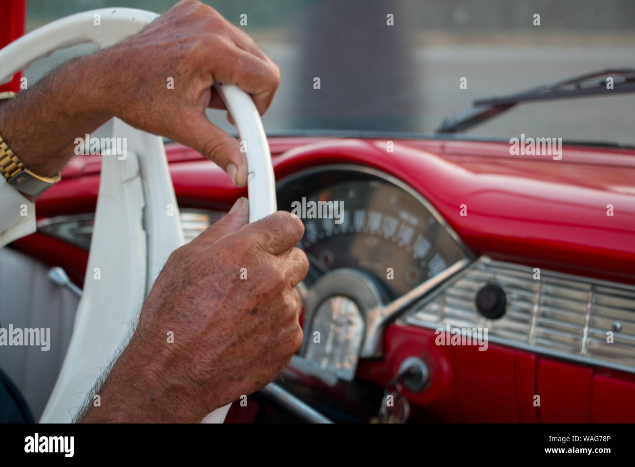 The hands of an older man at the wheel driving a lovely classic car ...