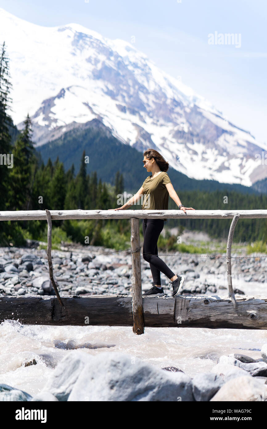Hiker crossing raging river over the log bridge in washington Stock ...