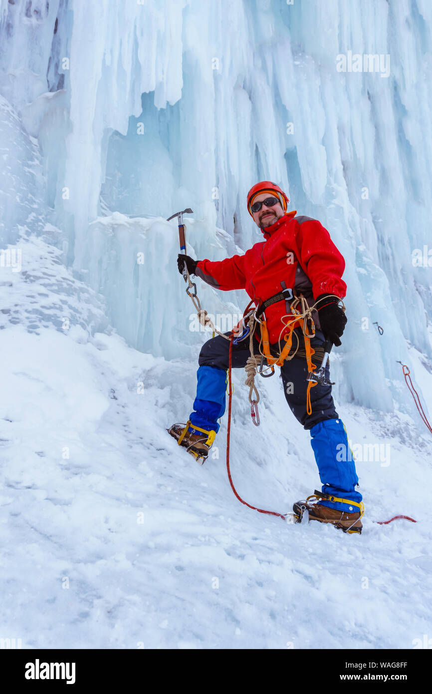 climber with ice axe storms the vertical wall of the glacier and looks ...