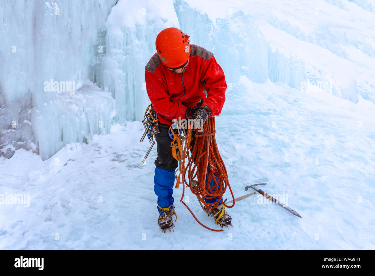 ice climber standing on the snow under the glacier is preparing a rope ...