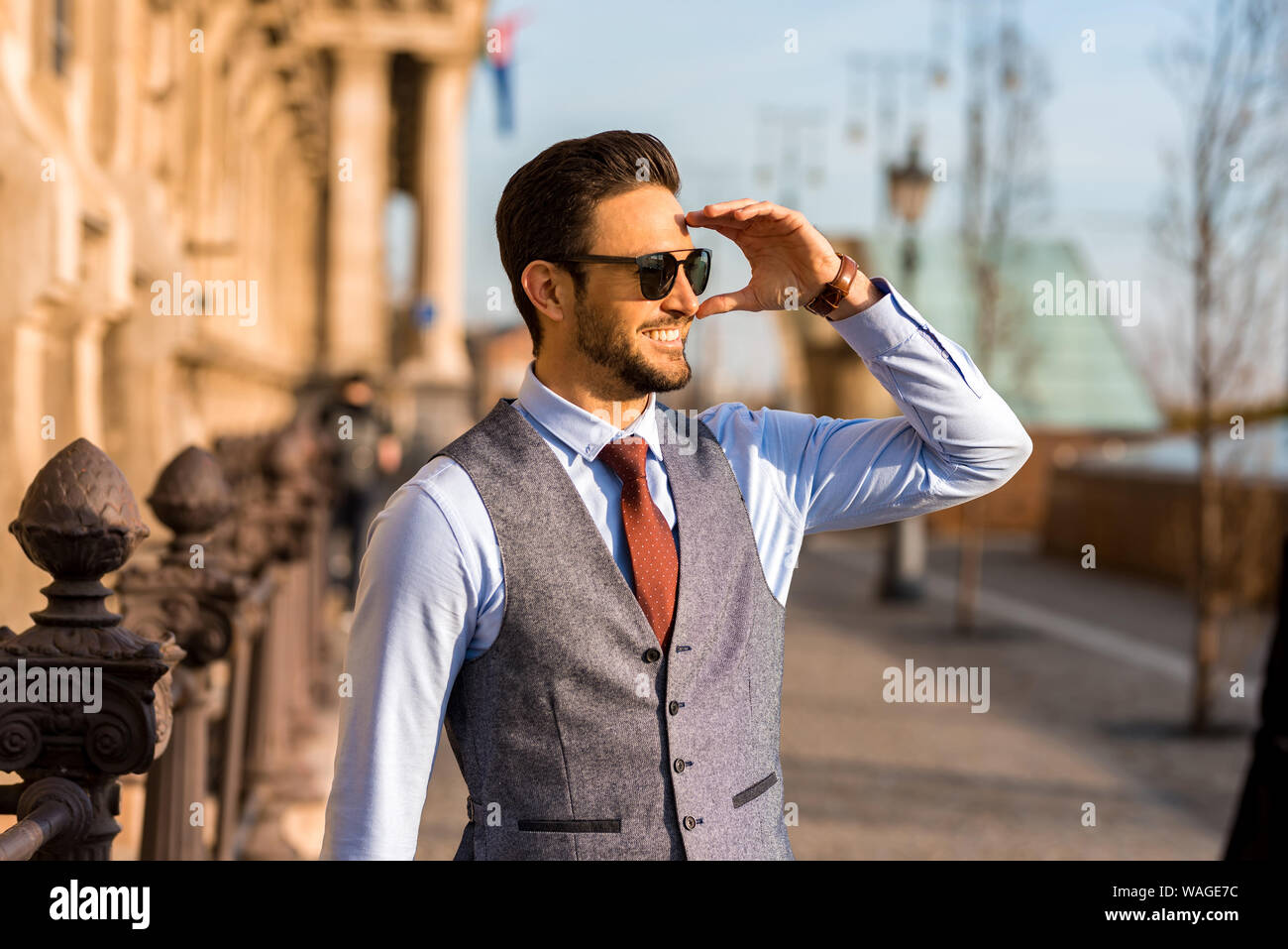 A handsome elegant man walking on the streets and covering his face on ...