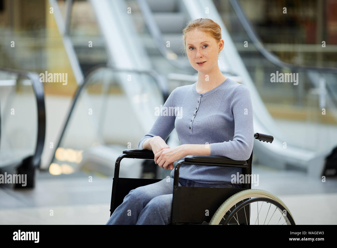 Portrait of red-haired female patient sitting in wheelchair and looking ...