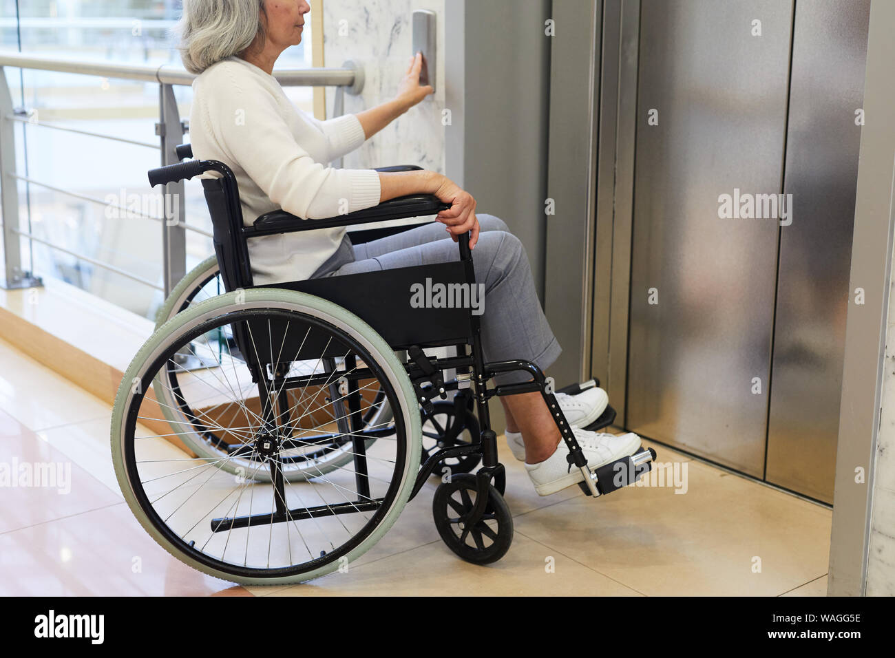Senior woman sitting in wheelchair and pushing the button she using the ...