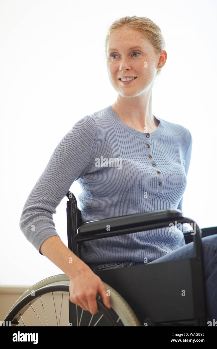 Young red-haired female patient going in wheelchair and smiling Stock ...