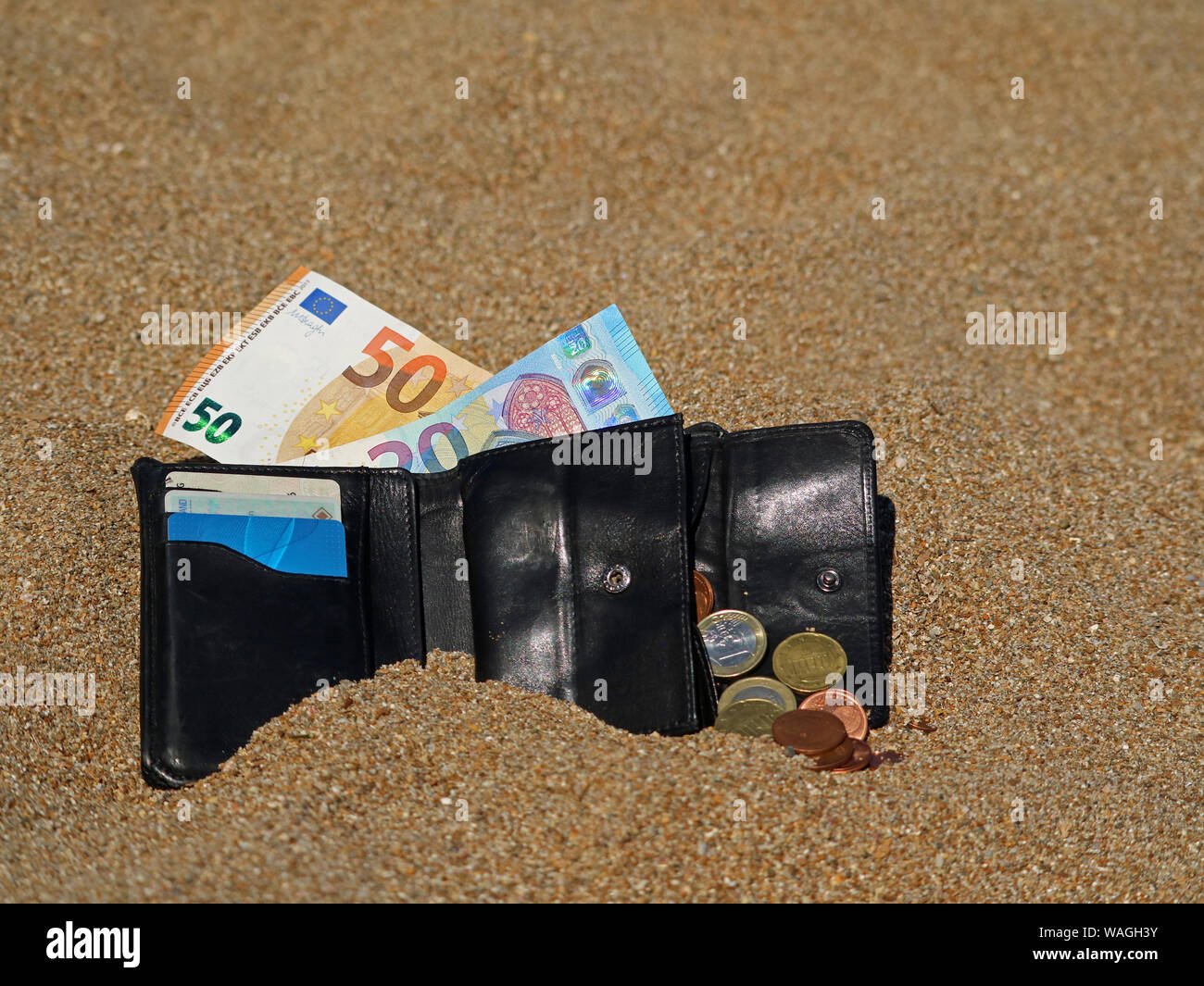 open black wallet with euro banknotes and coins in the sand on beach ...