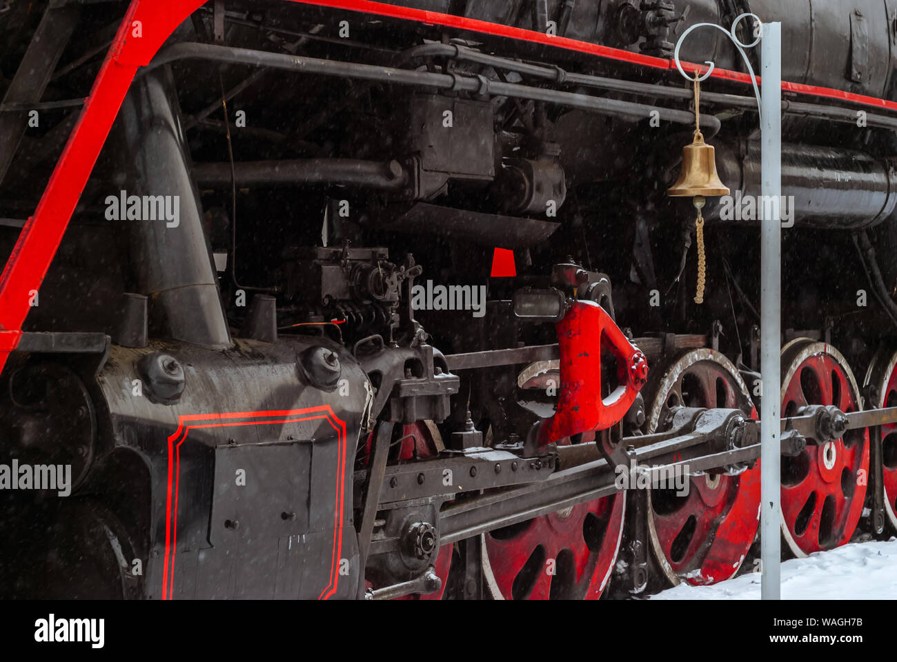 closeup of a steam locomotive wheels with valve gear and station bell ...