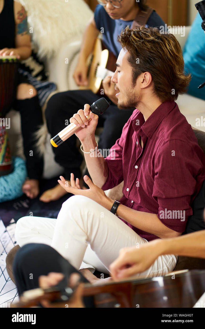 Man playing a guitar and singing into a microphone hi-res stock ...