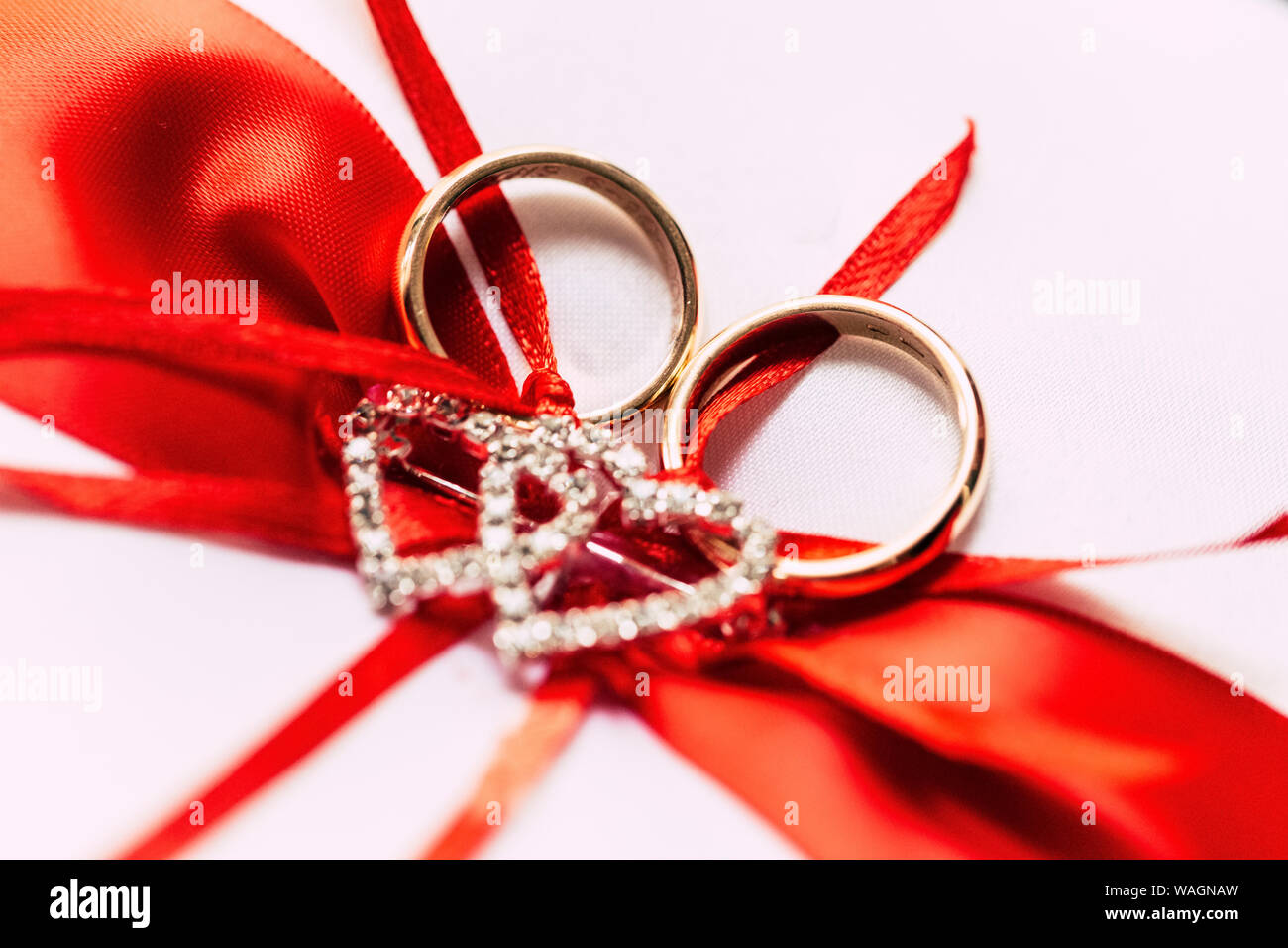 Gold wedding rings red ribbon hi-res stock photography and images - Alamy