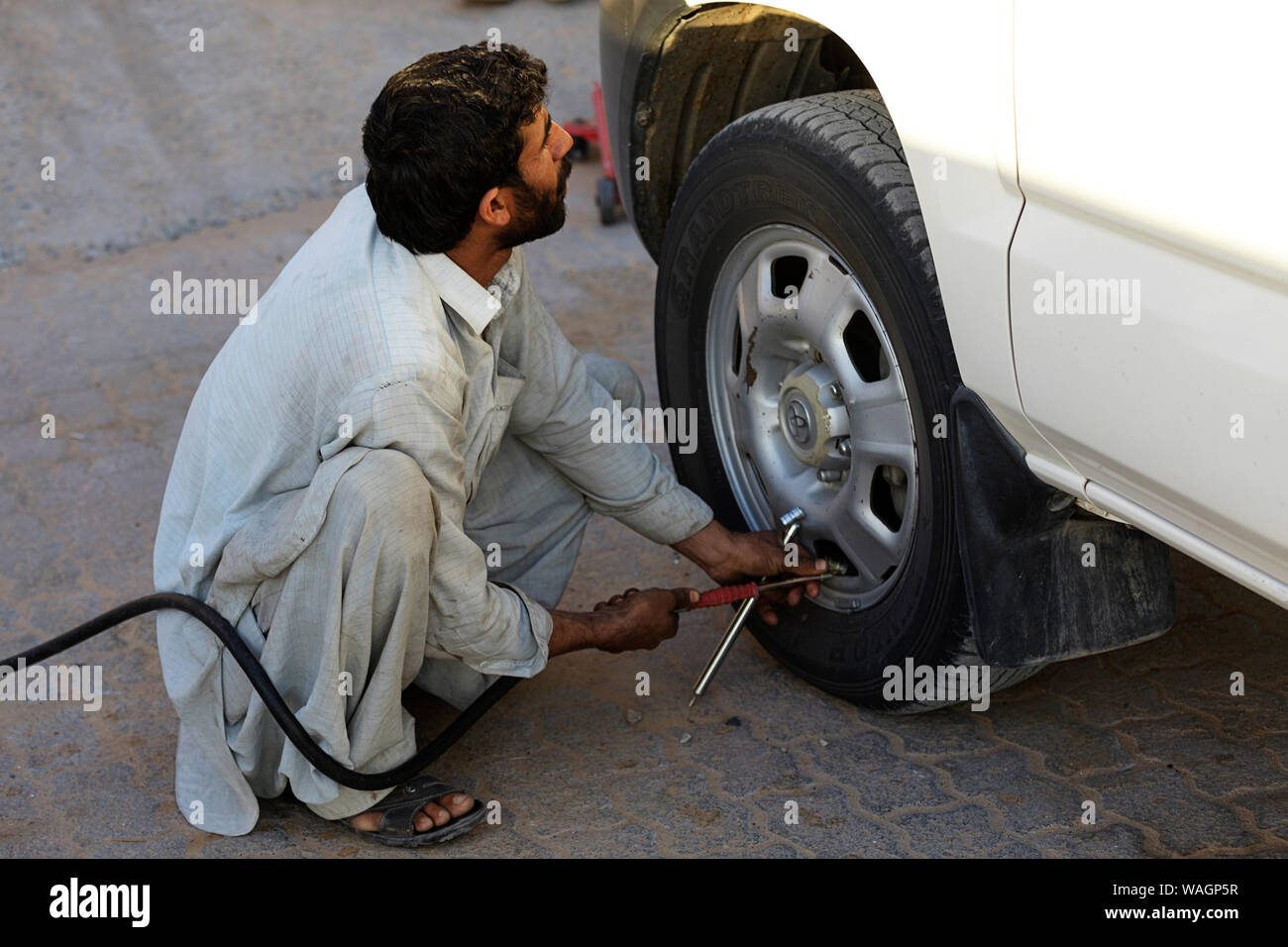 Mechanic fixing a car wheel, Oman Stock Photo - Alamy