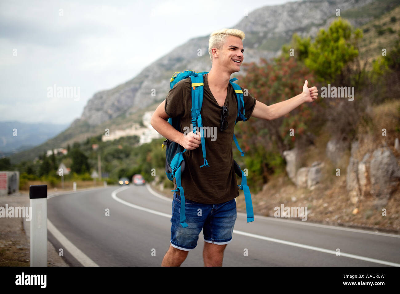 Travel man backpacking hitchhiking on road trip hitching a ride from ...
