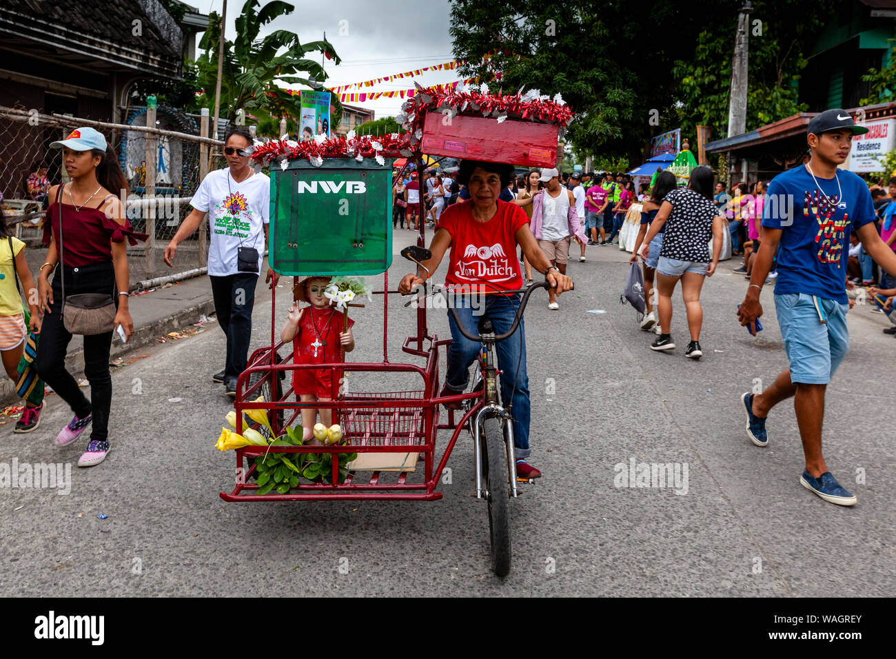 A Filipino Woman Cycles Through The Streets Of Kalibo With A Santo Nino ...