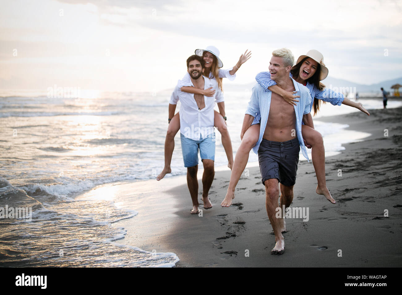 Friends having fun on the beach under sunset sunlight Stock Photo - Alamy