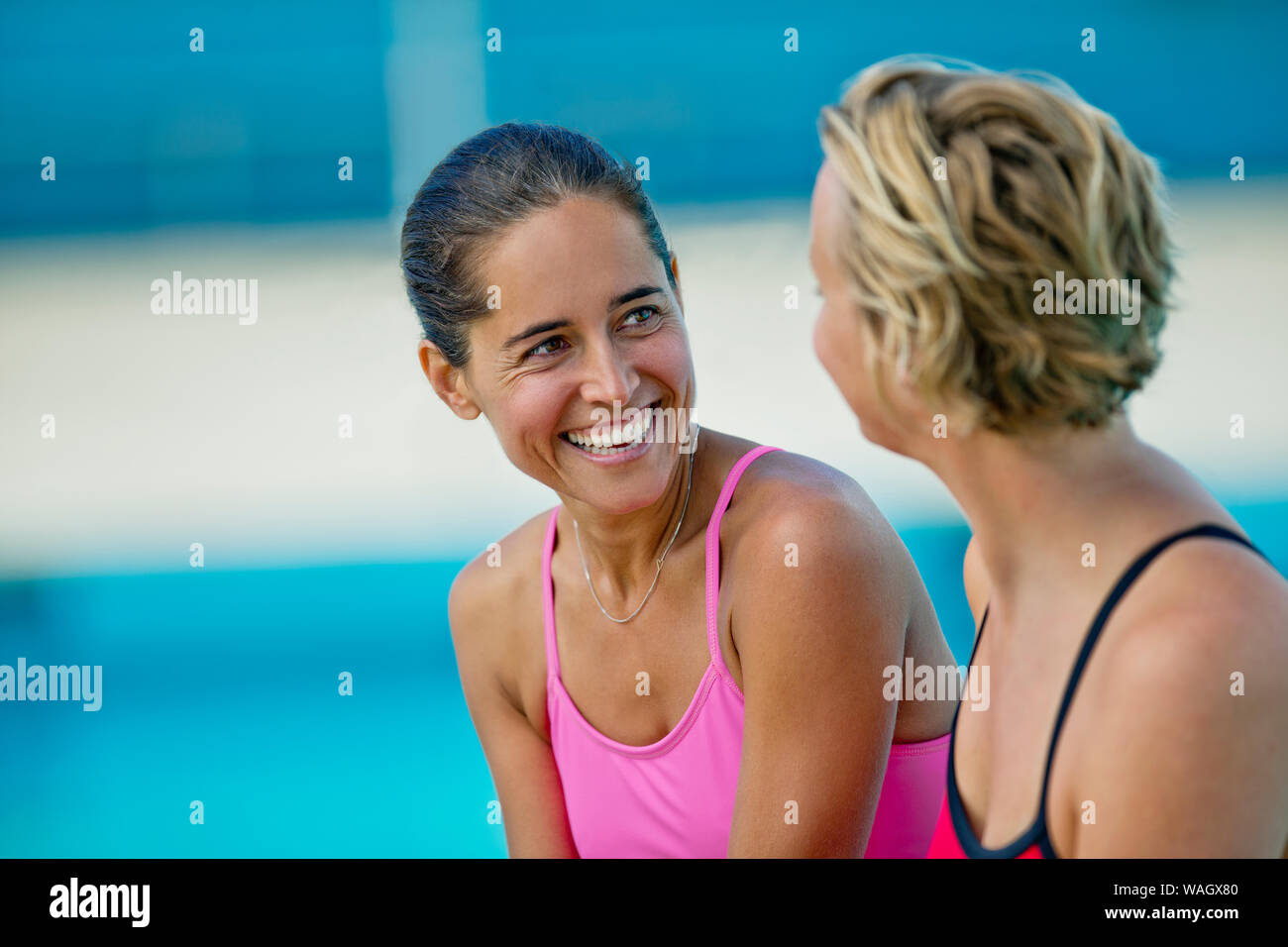 Two happy friends sit pool side Stock Photo - Alamy