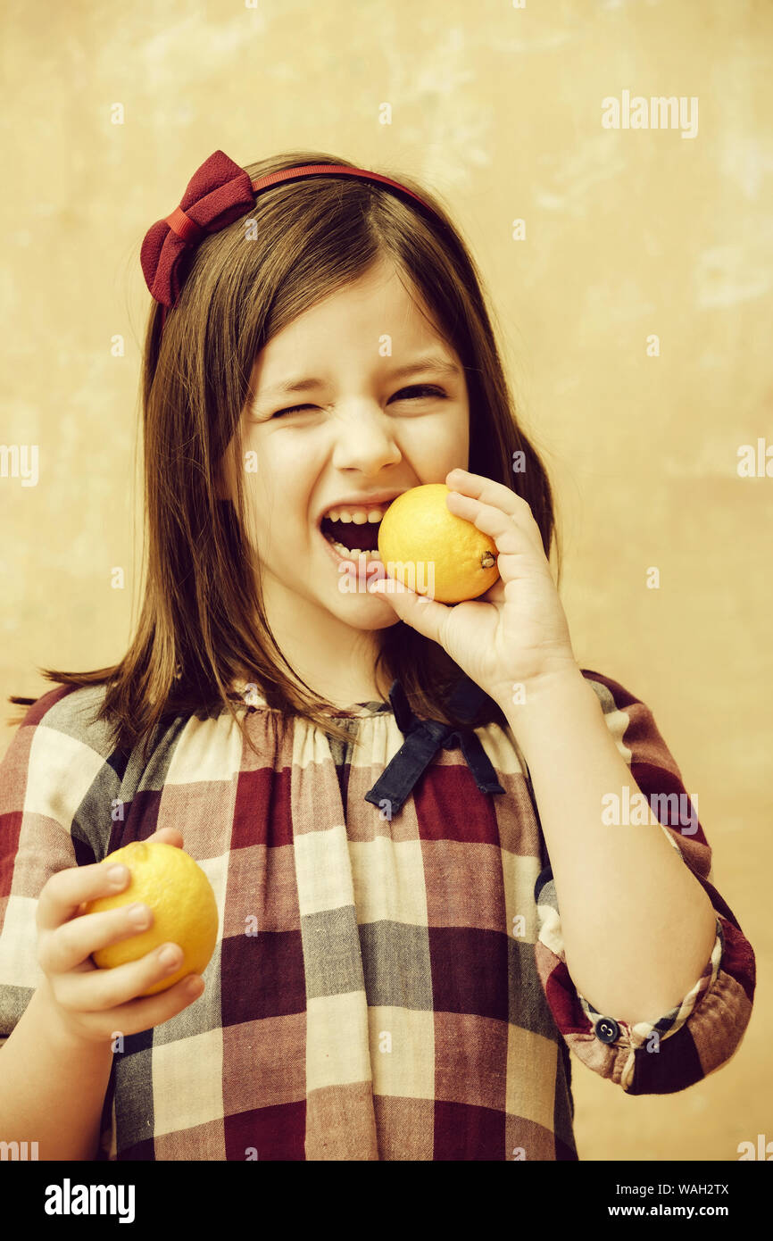 kid or girl with winking eye eating lemons Stock Photo - Alamy
