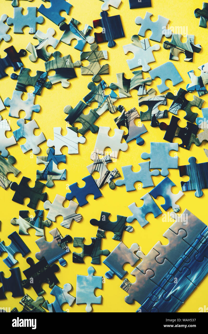 A lot of blue puzzle pieces on a yellow background. Vertical. Top view ...