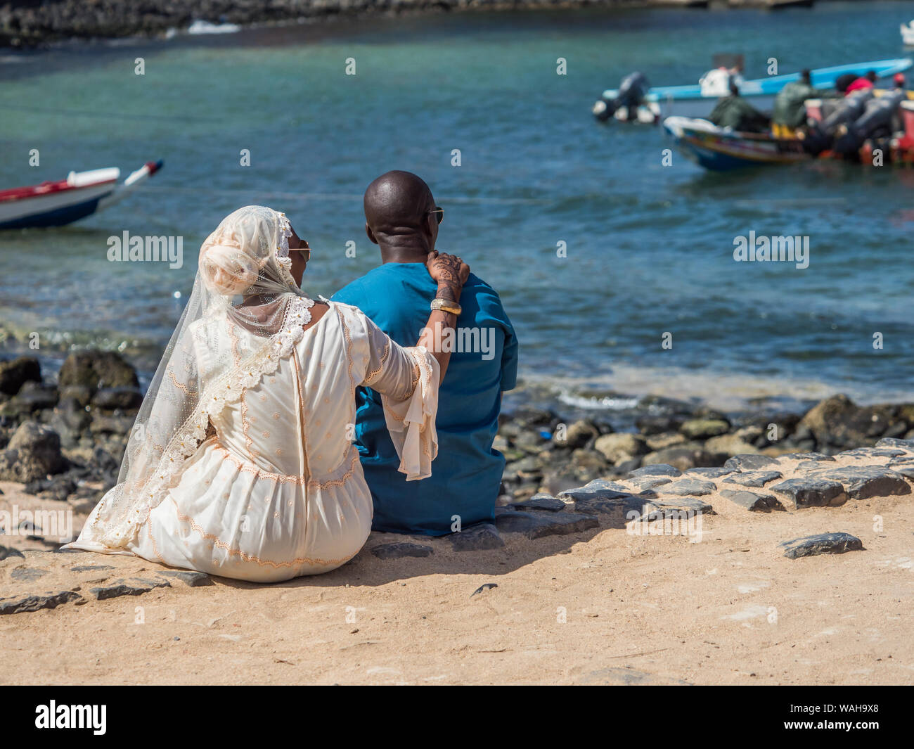 A view of a Senegalese couple in wedding dress sitting by the ocean on ...