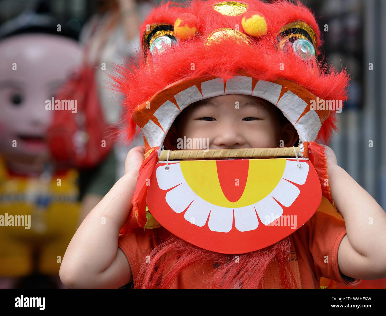 Happy little Chinese boy posing for the camera with a traditional lion ...