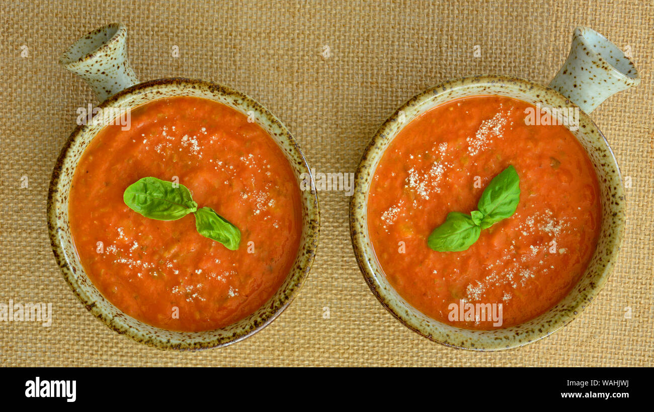 Homemade zesty tomato basil soup in rustic bowls in horizontal format ...