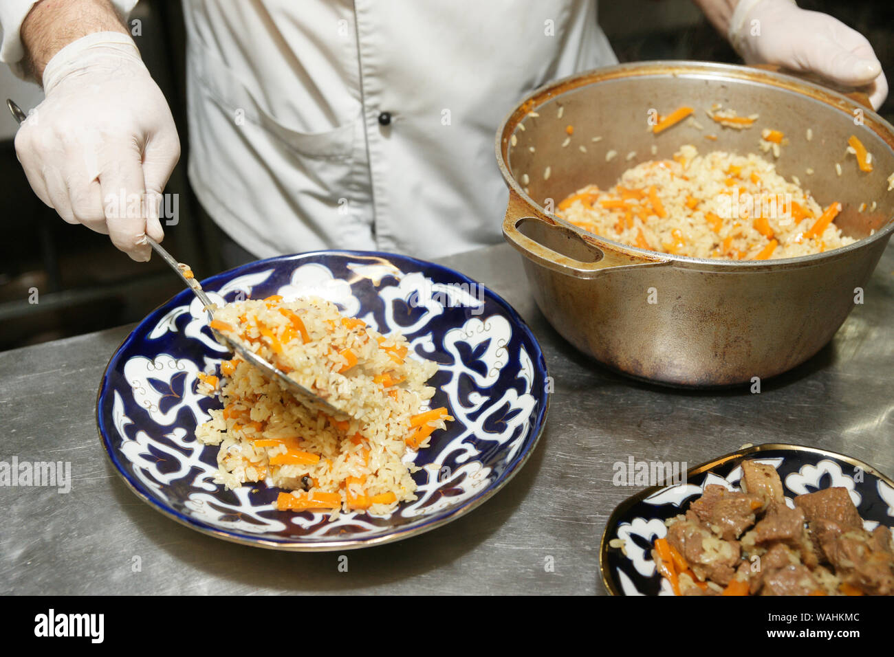 Gloved cook is serving traditional Middle Eastern pilaf, commercial ...