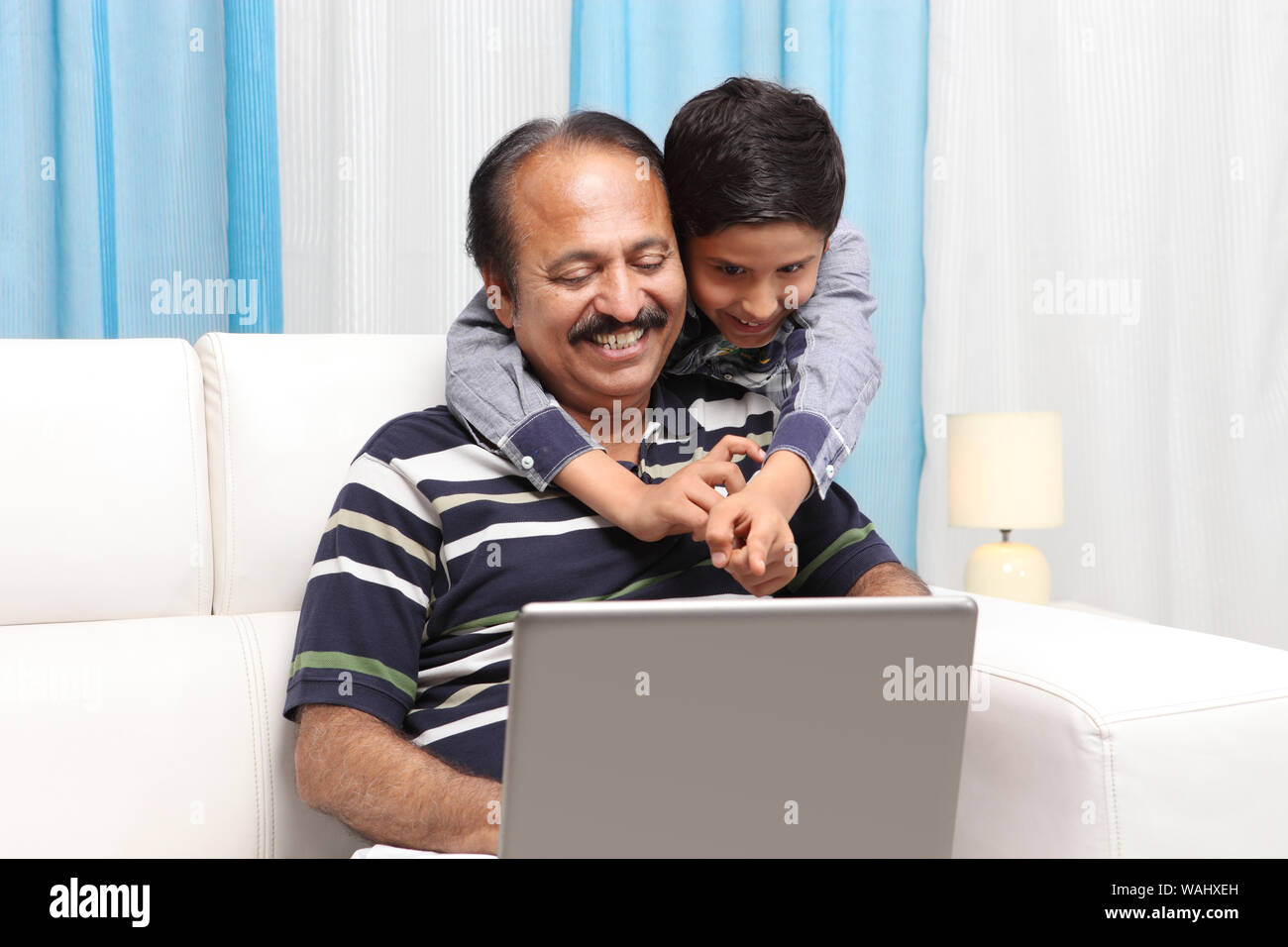 Indian old man assisting his grandson in using a laptop Stock Photo - Alamy