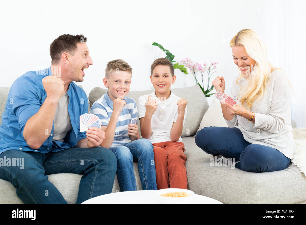 Happy family playing card game on living room sofa at home and having ...