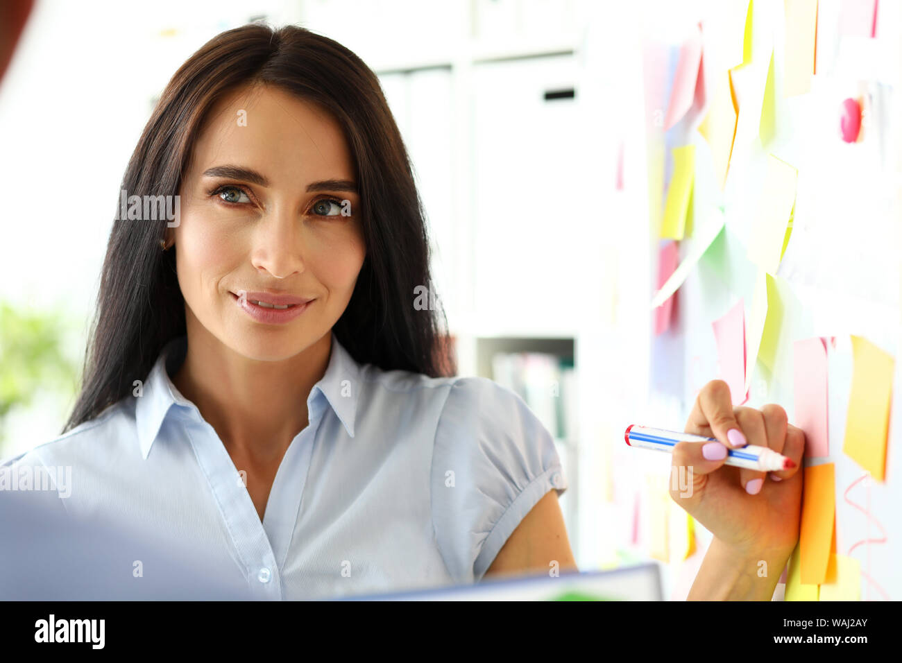 Beautiful female clerk drawing something on whiteboard during business ...
