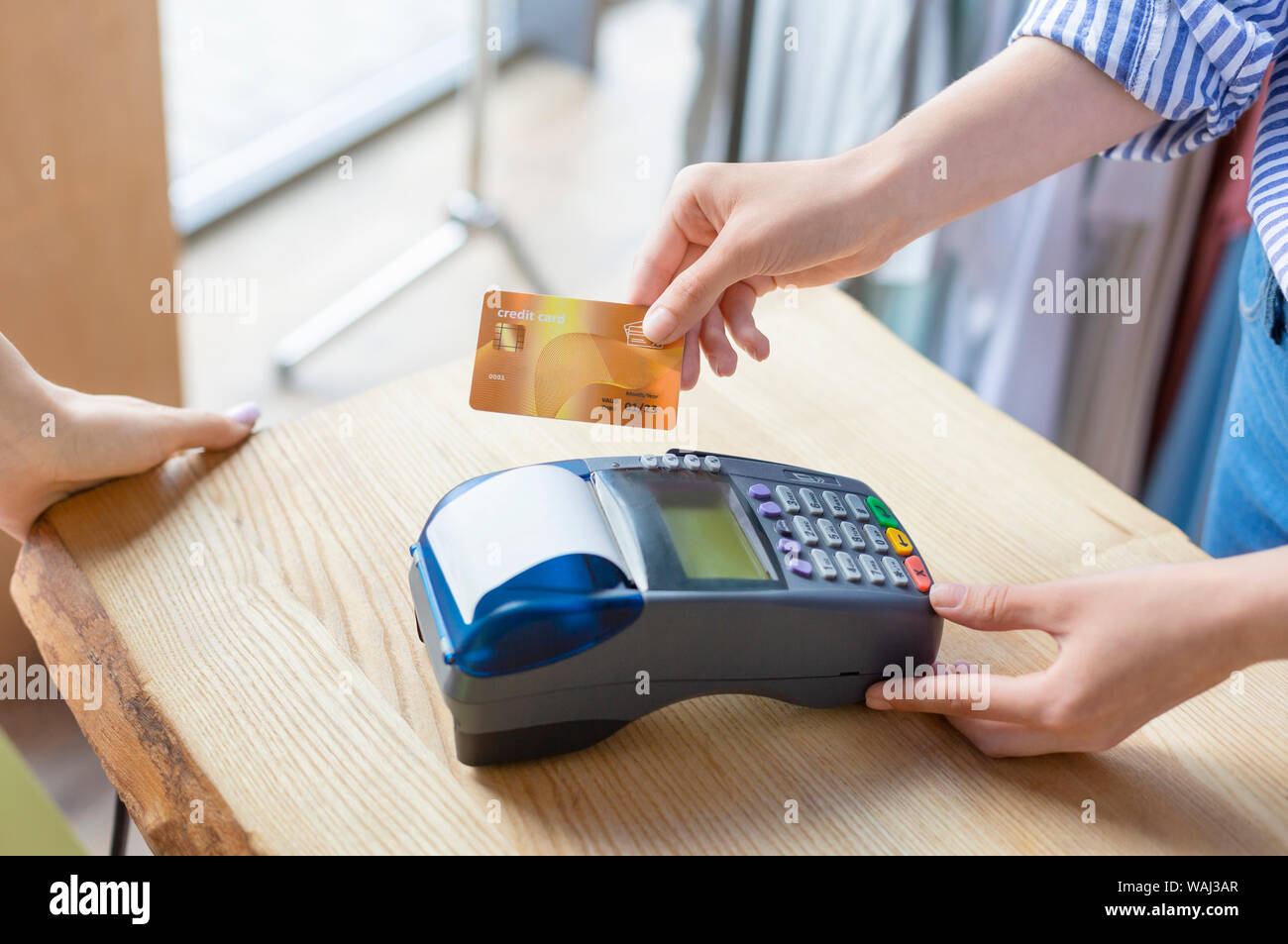 Female sales assistant swiping credit card at boutique Stock Photo - Alamy