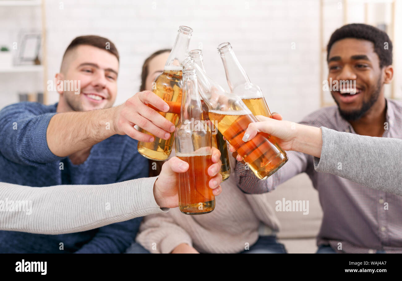 Cheers. Friends clinking beer bottles at home Stock Photo - Alamy