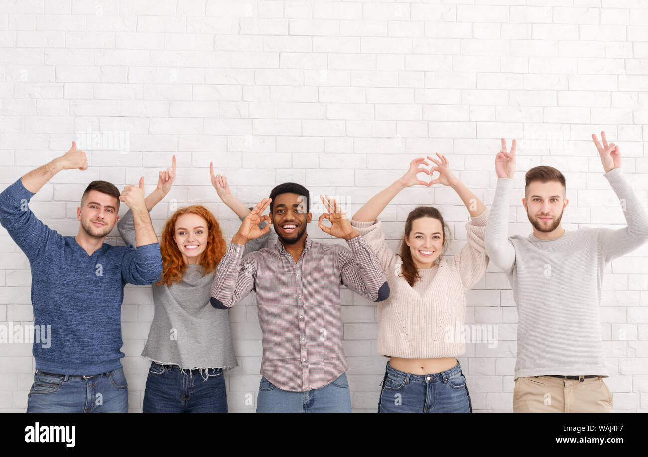 Happy friends gesturing with hands over white brick wall Stock Photo ...