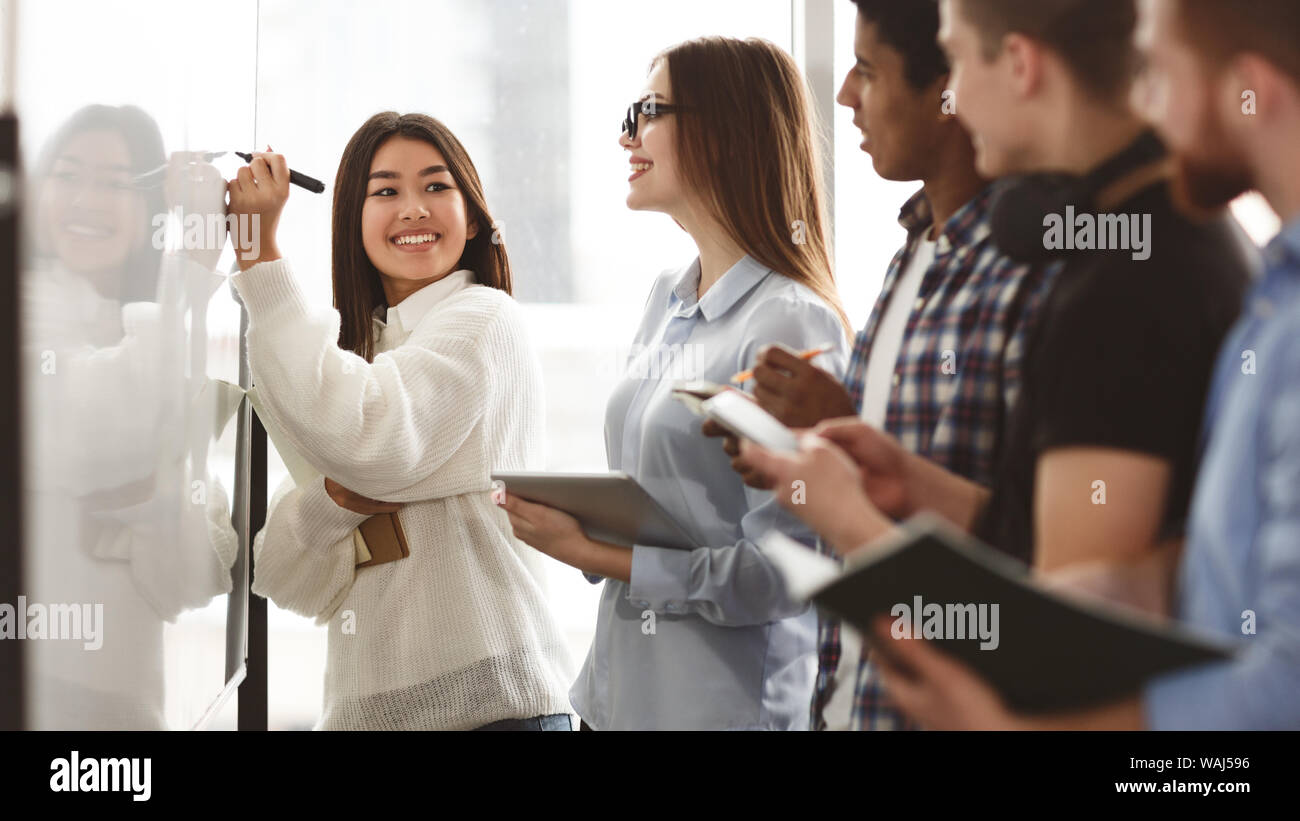 Students discussing tasks on whiteboard in classroom Stock Photo - Alamy