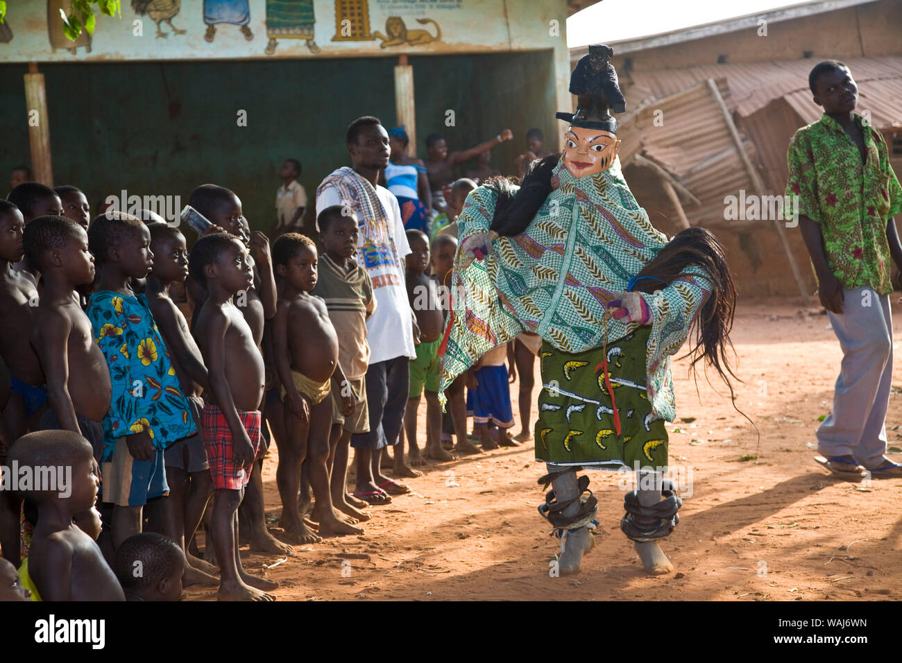 West Africa, Benin. Men and children watch Gelede Mask Dancers perform ...