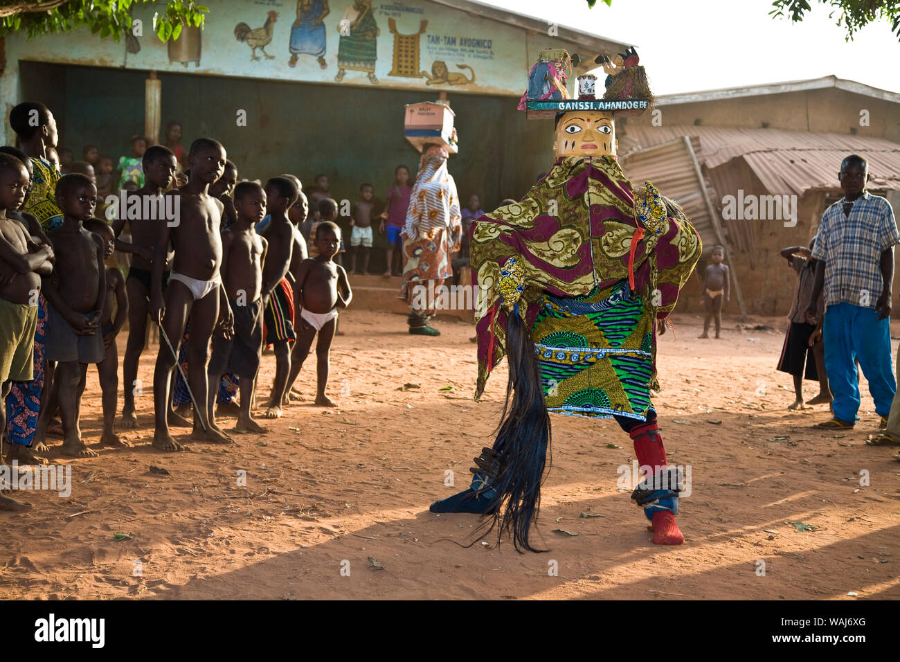 West Africa, Benin. Men and children watch Gelede Mask Dancers perform ...