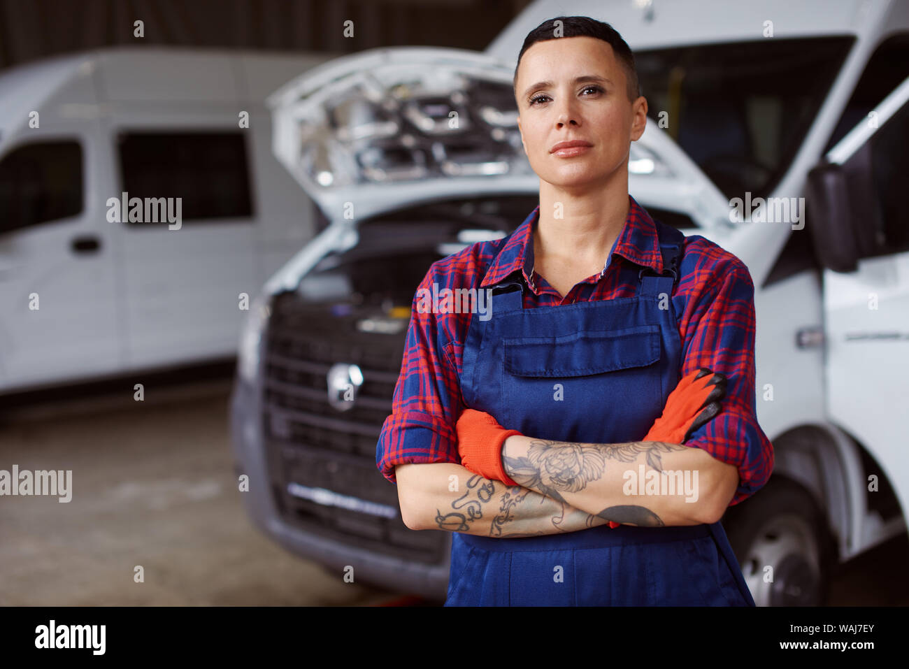 Female auto mechanic in denim overalls poses at the camera with her ...