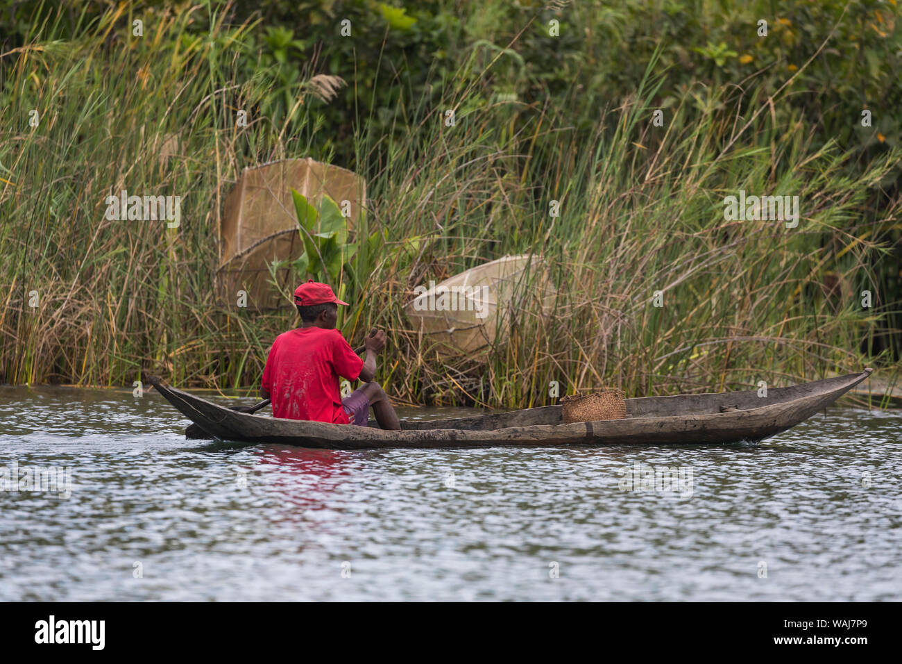 Africa, Madagascar, Lake Ampitabe. Fisherman paddling his dugout canoe ...