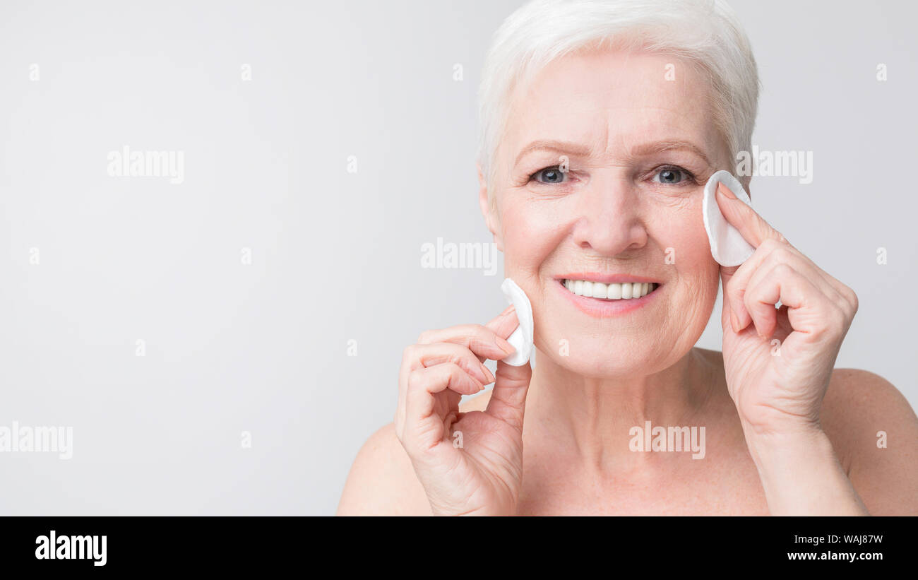 Charming senior woman cleansing her face with cotton pads Stock Photo ...