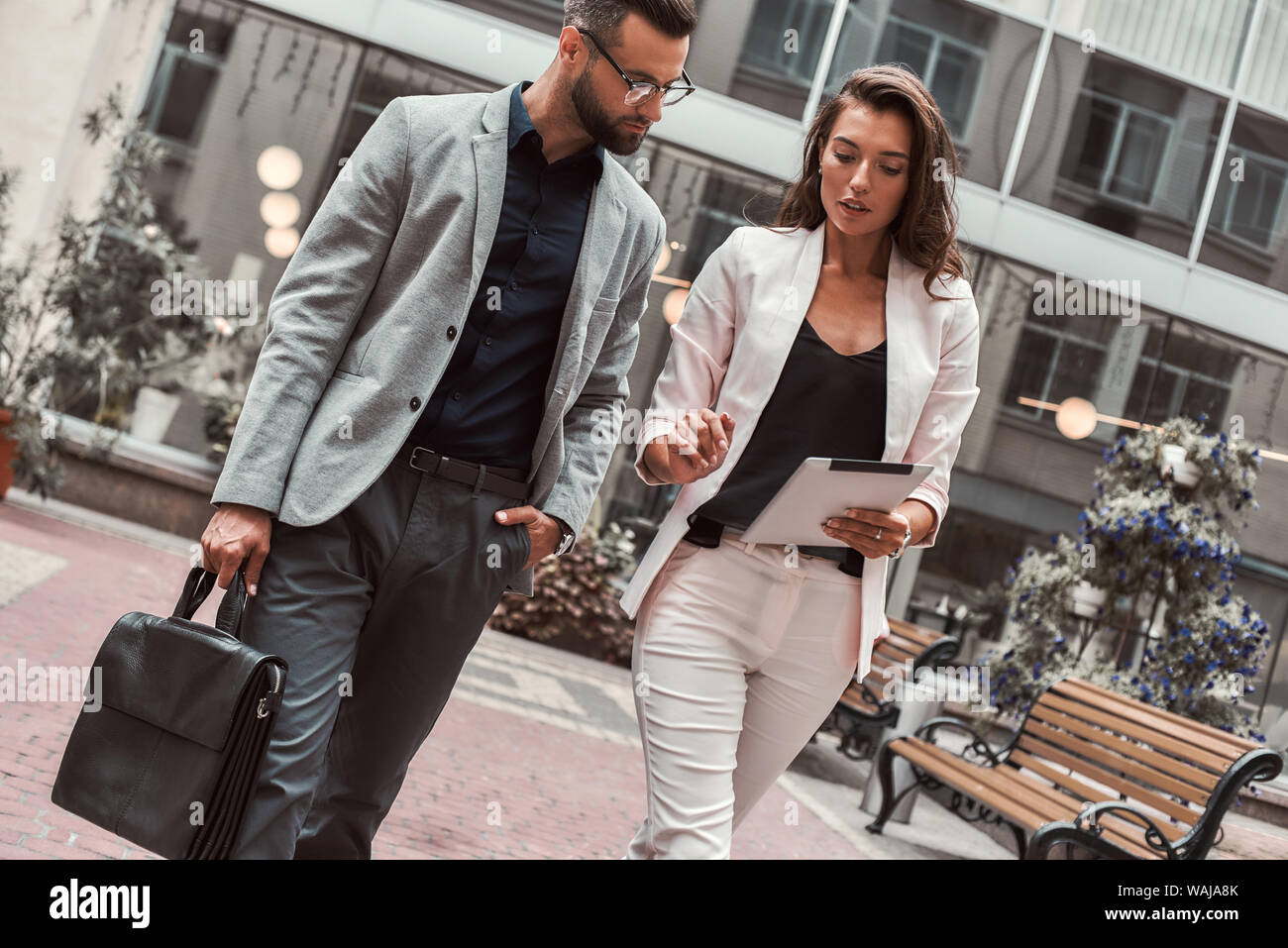 Cropped portrait of man and woman talking to each other while walking ...