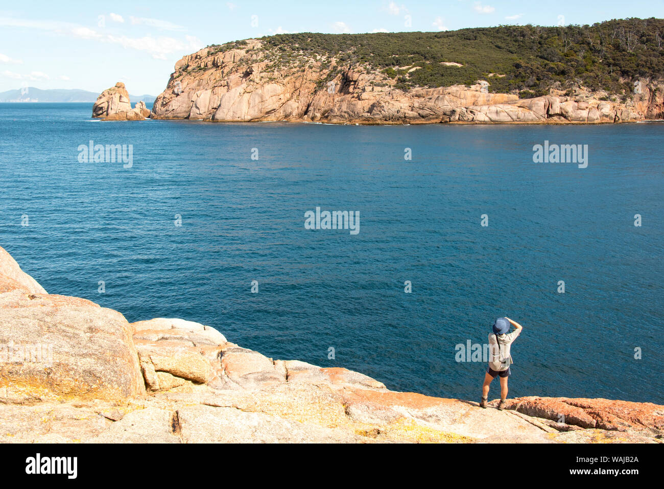 Australia, Tasmania, Maria Island. Hiker photographing from edge of ...