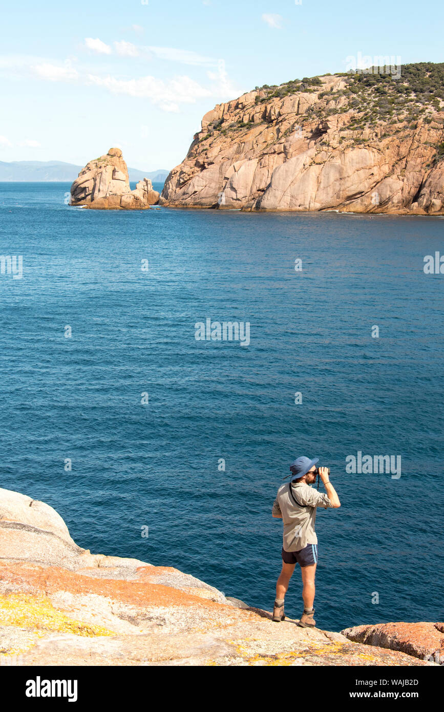 Australia, Tasmania, Maria Island. Hiker viewing from edge of rock ...