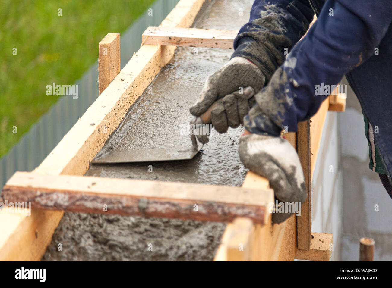 Worker levels concrete in formwork using a trowel Stock Photo - Alamy