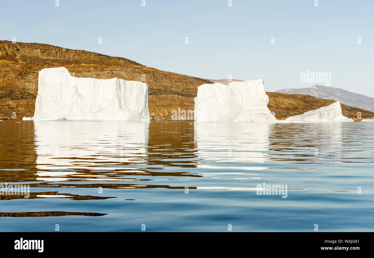 Landscape with steep yellow cliffs and icebergs in the Uummannaq fjord ...