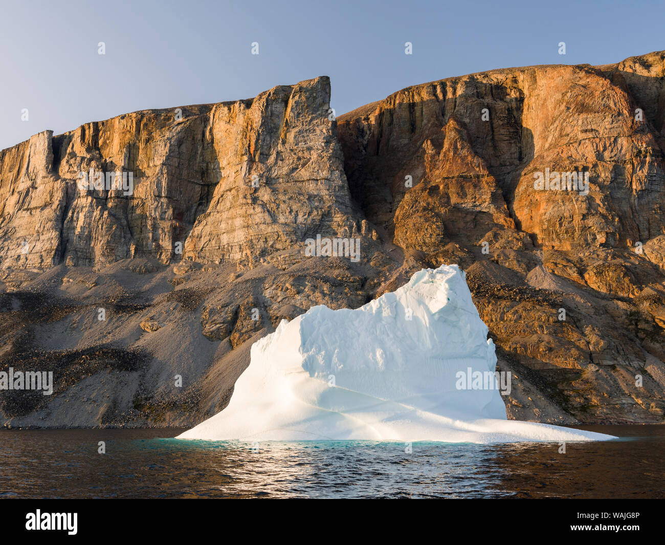 Landscape with steep yellow cliffs and icebergs in the Uummannaq fjord ...