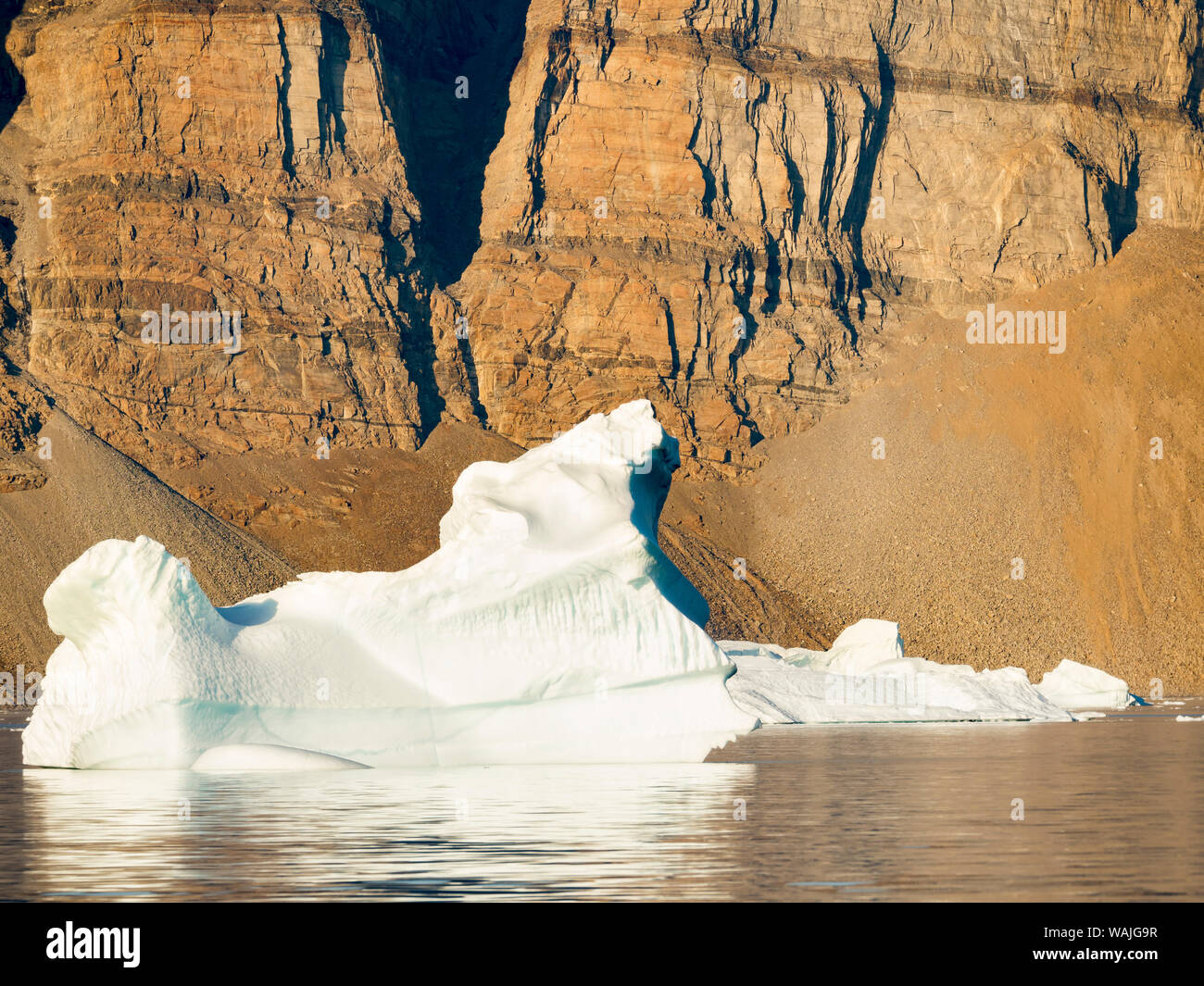 Landscape with steep yellow cliffs and icebergs in the Uummannaq fjord ...