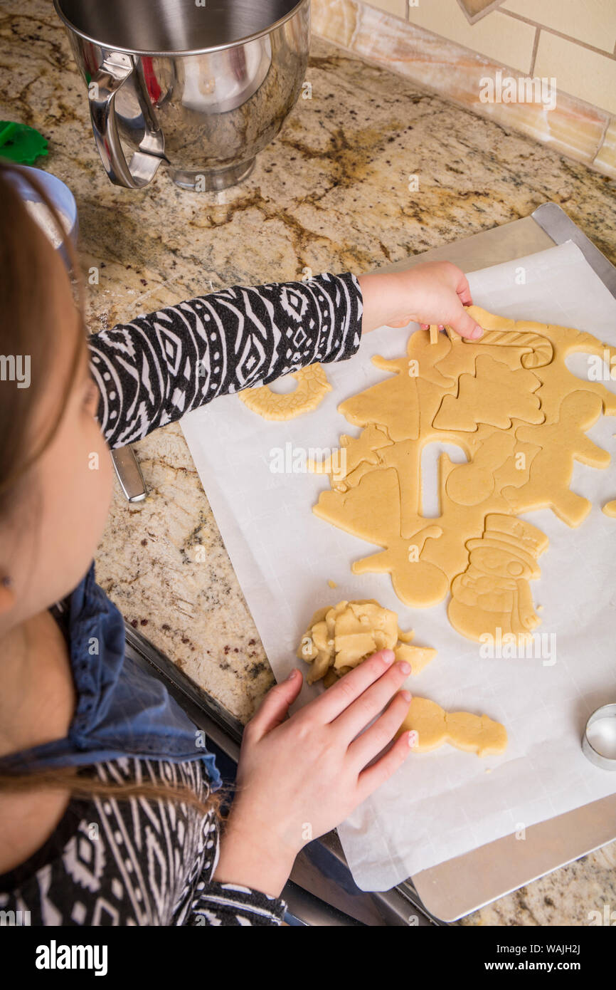 Ten year old girl removing excess cookie dough from around the cut-out ...
