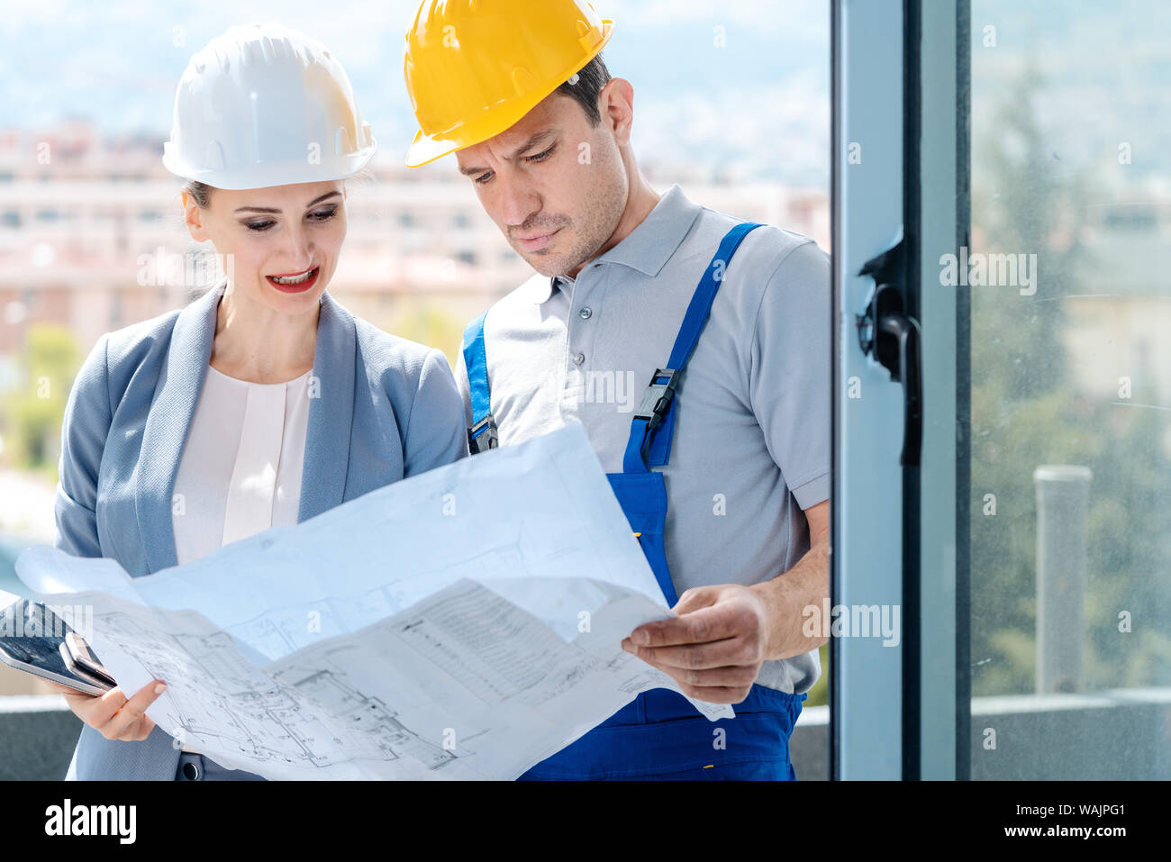 Principal and builder reading blueprints on construction site Stock ...