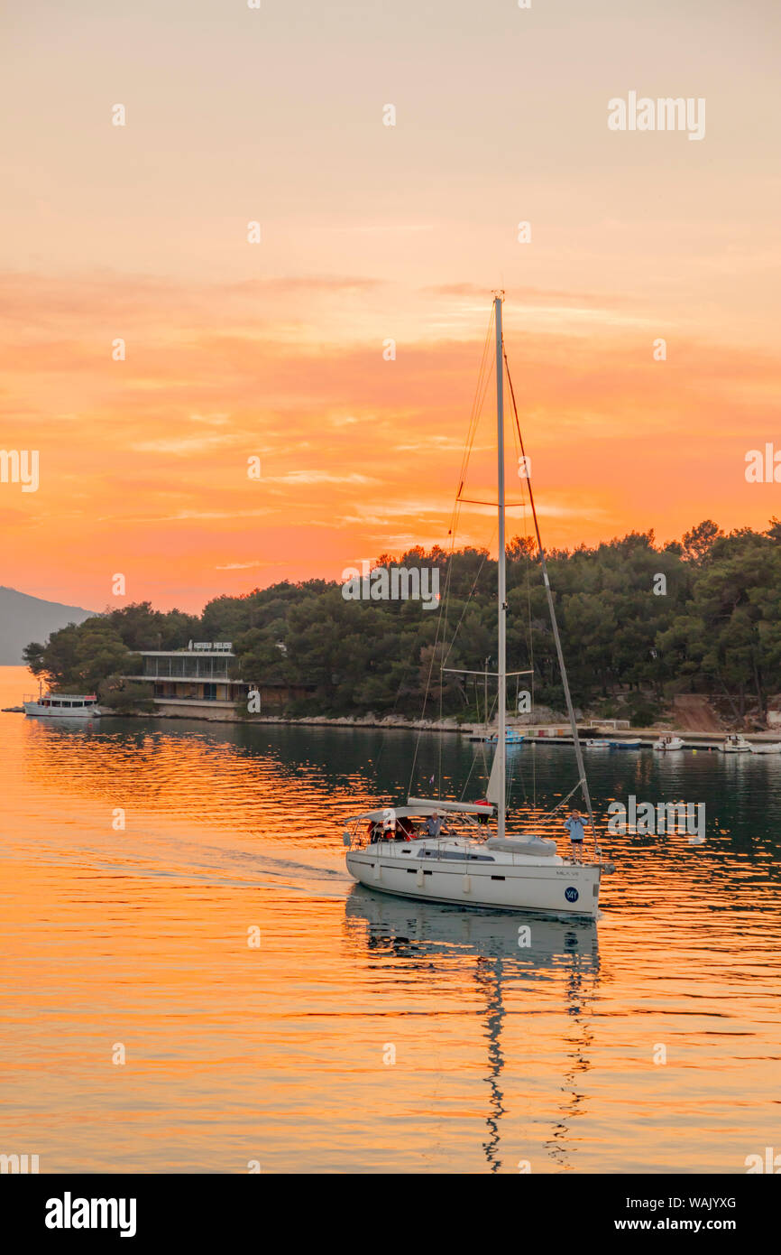 Croatia, Stari Grad. Sailboat coming into harbor at sunset. Credit as ...