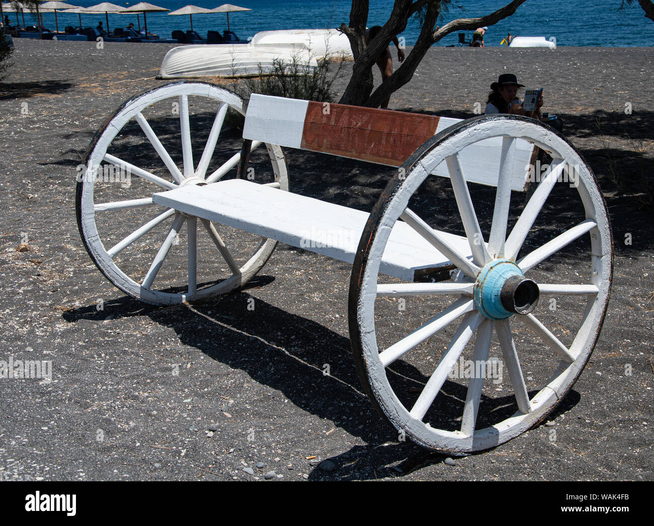 Perissa, Greece - July 11 2019: A bench made with two old wagon wheels ...